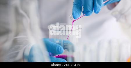 Scientist pour pink liquid from flask in medical chemistry laboratory ...