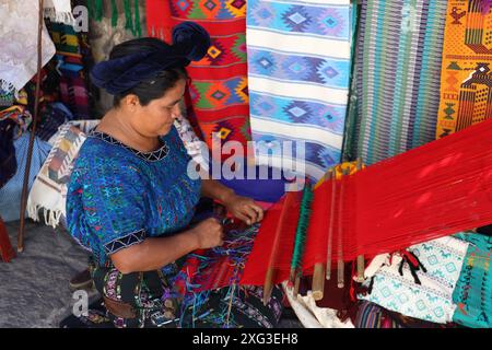 Indigenous Guatemalan lady using a backstrap loom to hand weave fabrics ...
