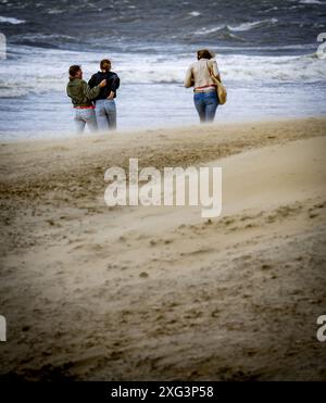 SCHEVENINGEN - Walkers have difficulty with the wind along the beach of ...