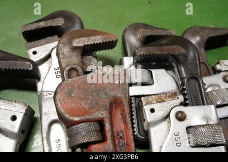Old rusty pipe wrench and other tools on green background, close up ...