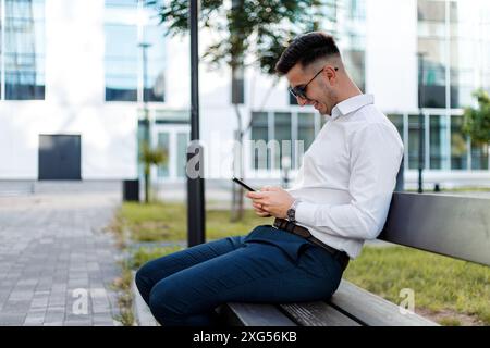 A businessman interacts with his mobile phone while sitting in an ...