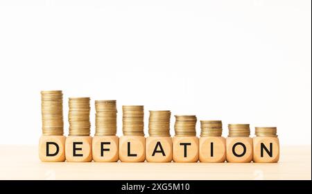 Deflation concept. Text on wooden blocks and stacked coins. Copy space ...