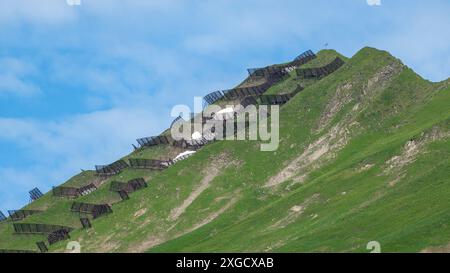 Avalanche barriers on the steep mountain slope above a village in the ...
