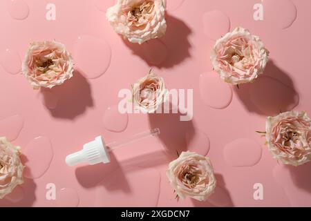 Beautiful rose flowers, pipette and drops of cosmetic serum on pink ...