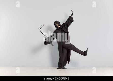 Man in grim reaper death costume swings scythe, having fun on Halloween ...