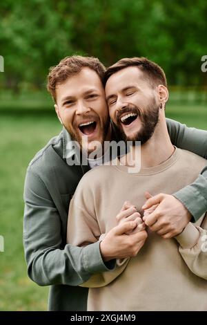 Two bearded gay men share a laugh while enjoying coffee in a lush green ...