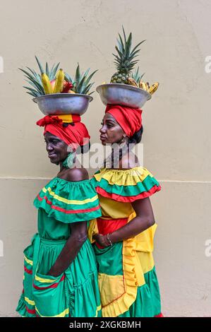 The Palenqueras of Cartagena, dressed in vibrant, colorful outfits with ...