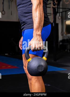 Closeup of man holding heavy kettlebell at gym with blurred background ...