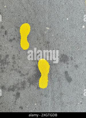 Yellow footprint painted on asphalt road. Walkway lane traffic sign ...