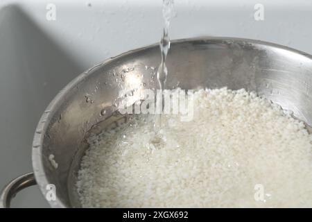 Pouring water into bowl with rice in sink, closeup Stock Photo - Alamy