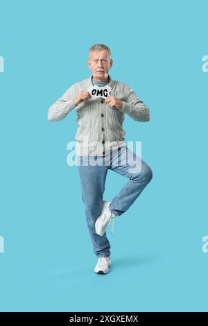Shocked senior man holding speech bubble with word OMG on yellow ...