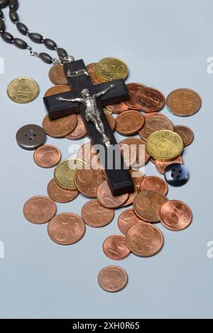 Crucifix with coins and buttons, church and money Stock Photo - Alamy