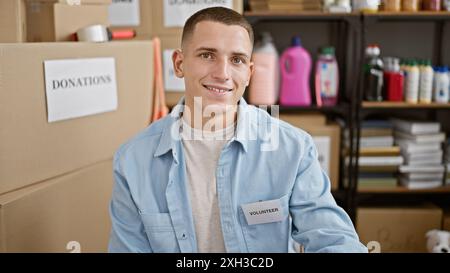 Young hispanic man wearing volunteer t shirt at donations stand making ...