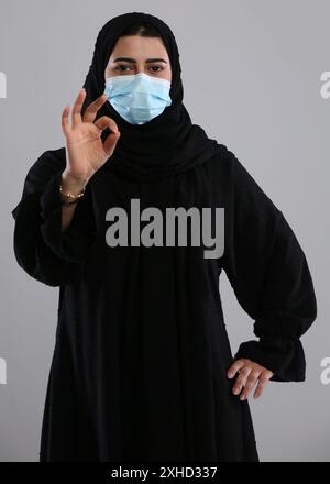 saudi arabian woman in hijaab wearing mask looking at camera with stop sign Stock Photo - Alamy