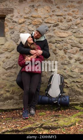 couple of young mountaineers hugging leaning on a shelter wall in the ...