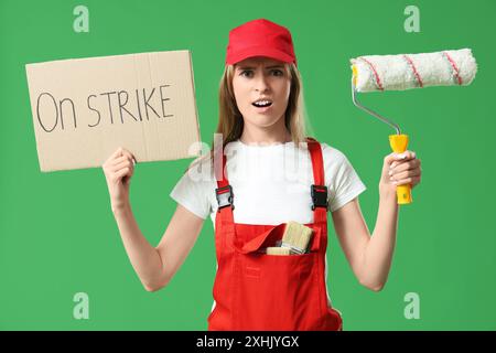 Protesting female painter holding placard with text STRIKE on green ...