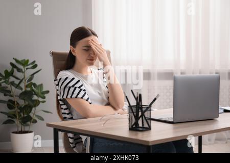Embarrassed woman at wooden table with laptop in office Stock Photo - Alamy
