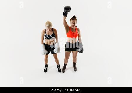Victorious female boxer raising hand in glove in triumph isolated on ...