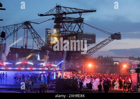 Festival visitors celebrate between excavators at the Melt Festival in ...