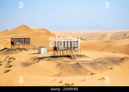 Desert hotel houses standing above the sands in the middle of Wahiba ...