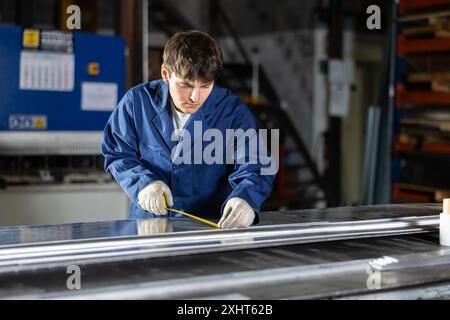 Guy measuring sheet of metal with tape measure Stock Photo - Alamy
