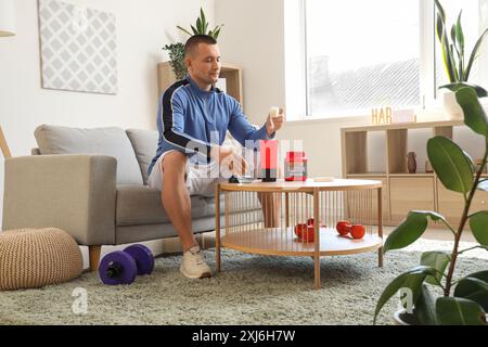 Sporty young man pouring protein powder into bottle at home Stock Photo ...