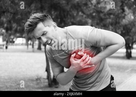 Heart attack. Man writhing in pain and pressing hands to chest on grey ...