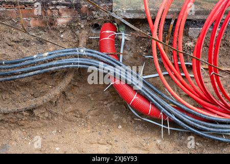 Network cables in red corrugated pipe are buried underground on the ...