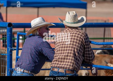 Two rodeo livestock wranglers talking before a rodeo in a small town in ...