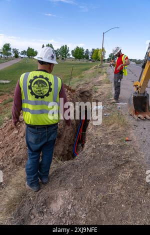 Workers installing plastic conduit for internet fiber optic cable ...