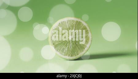 Composition of halved lime and white spots on green background Stock ...