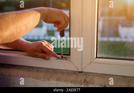 handyman adjusting white pvc plastic window indoors. worker using ...