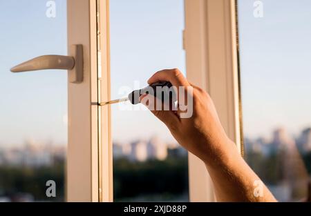 Worker adjusting installed window with screwdriver indoors, closeup ...
