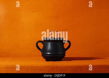 Mysterious black cauldron with witch legs protruding, On pumpkin orange ...
