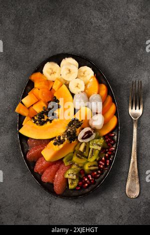 Sliced Kiwi fruits with fork in a glass bowl on turquoise pastel color ...