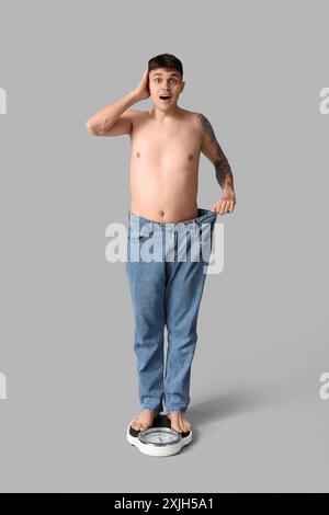 Shocked young man with scales on yellow background, closeup. Weight ...