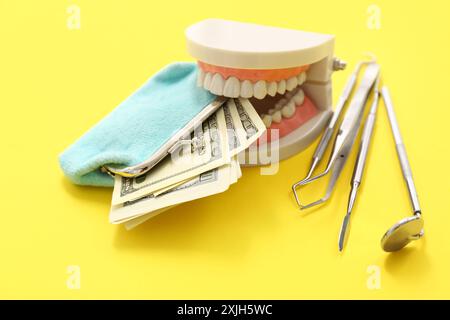 Model of oral cavity with teeth and dollar banknotes on light blue ...