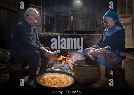 Flower Hmong man and woman shelling corn in their kitchen in Bac Ha ...
