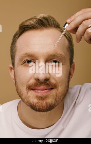 Young man using serum for skin care on white background Stock Photo - Alamy
