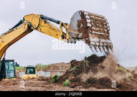 Excavator dropping a pile of loose dirt on the ground Stock Photo - Alamy