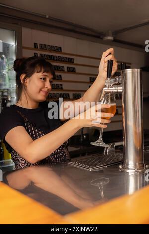 Smiling young waitress filling glass from beer tap at restaurant Stock ...