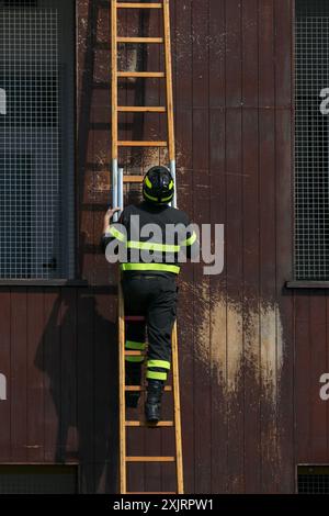 Firefighter in uniform with portective helmet climbing ladder during ...