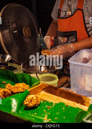 street food vendor preparing fried rice in large wok at busy outdoor ...