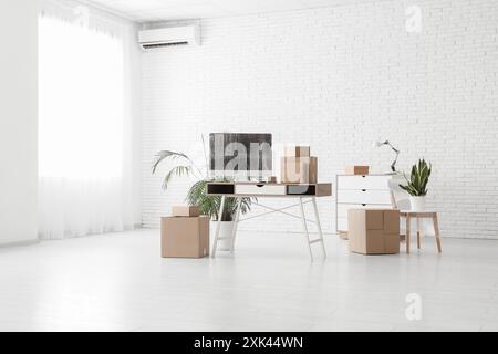 Workplace with wrapped computer monitor and cardboard boxes in office ...