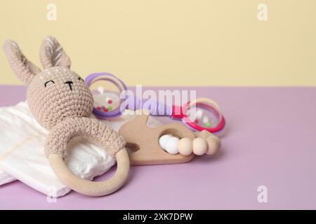 Baby rattles and diapers on lilac background Stock Photo - Alamy