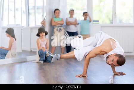 Young breakdancer demonstrating dance moves to group of tweens in studio Stock Photo - Alamy