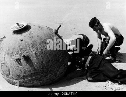 German soldiers defusing a sea mine washed up on the beach. Undated ...