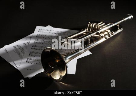 Shiny trumpet and music sheets on dark background. Wind musical ...