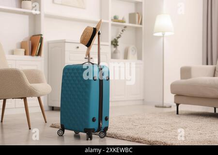 Light blue suitcase and straw hat indoors, space for text Stock Photo ...