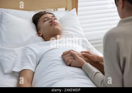 Coma patient. Sad young woman near her unconscious mother in hospital ...